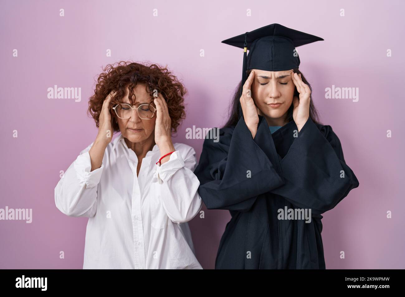 Hispanic mother and daughter wearing graduation cap and ceremony robe ...
