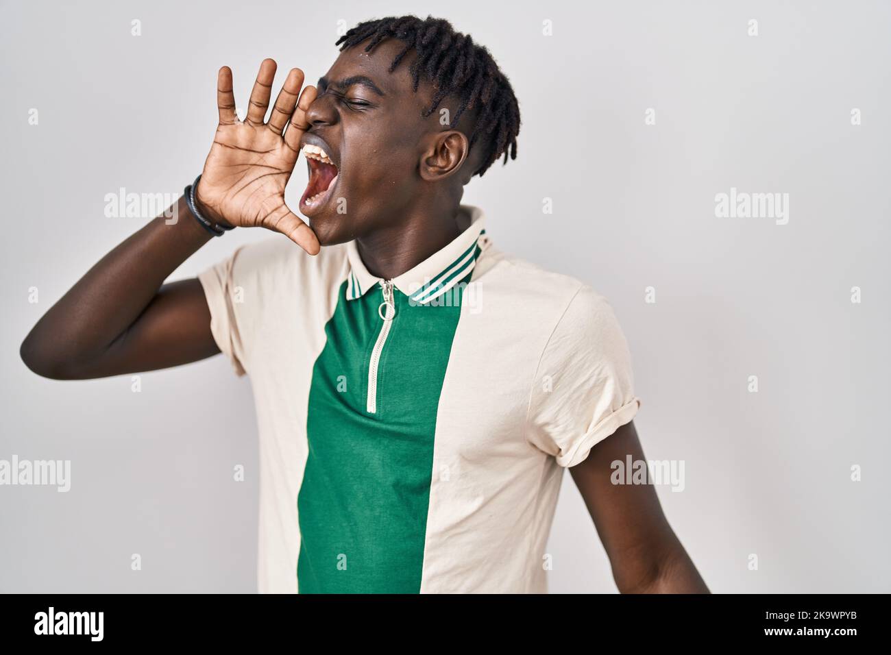 African man with dreadlocks standing over isolated background shouting ...