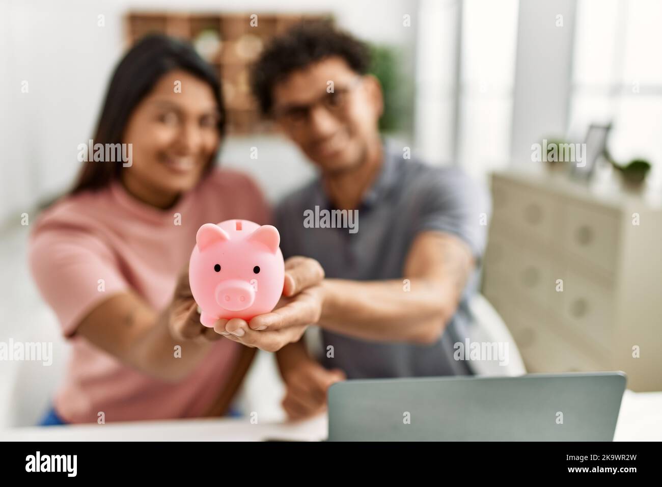 Young latin couple smiling happy holding piggy bank sitting on the ...