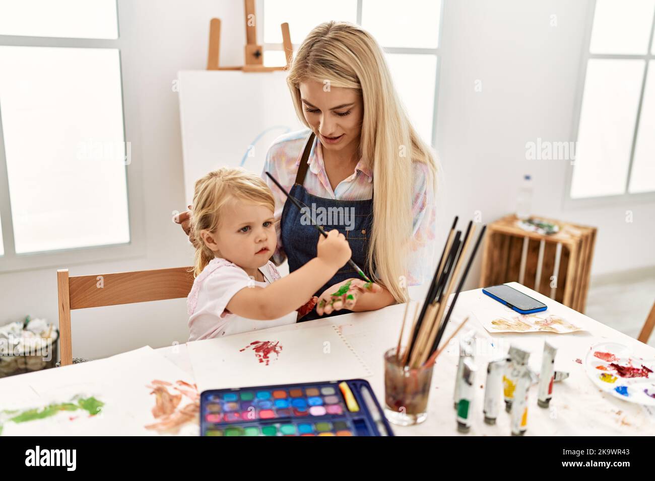 Mother and daughter smiling confident painting palm hands at art studio ...