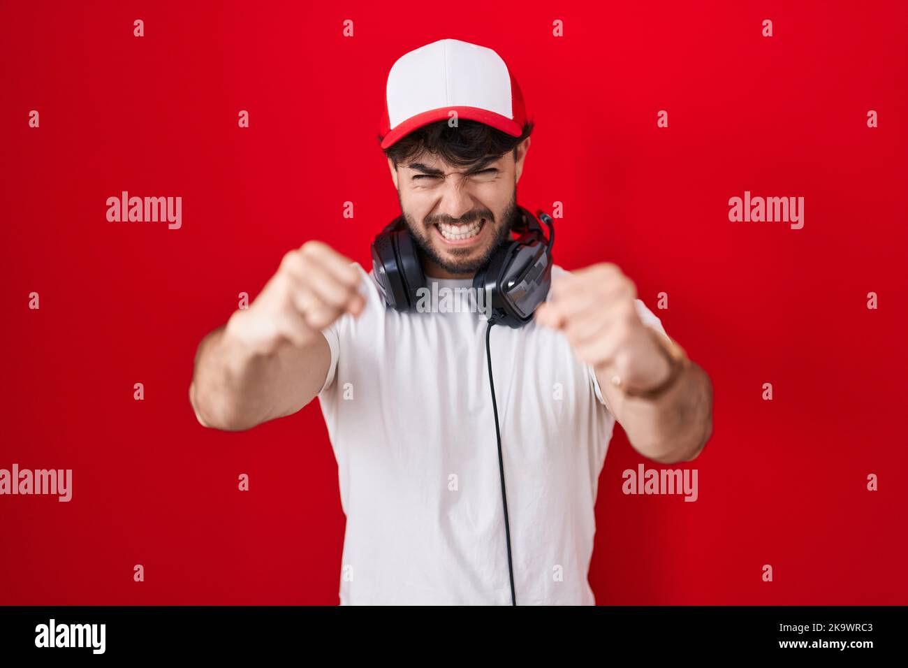 Hispanic man with beard wearing gamer hat and headphones angry and mad ...