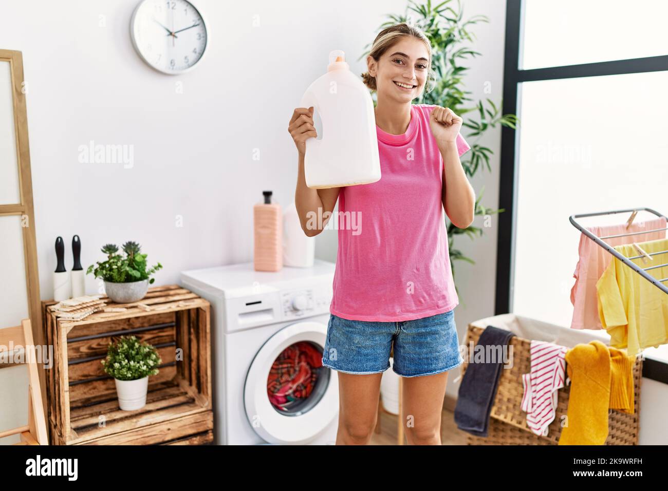 Young blonde woman doing laundry holding detergent bottle screaming ...