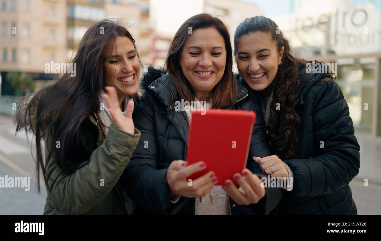 Mother and daugthers having video call hugging each other at street ...