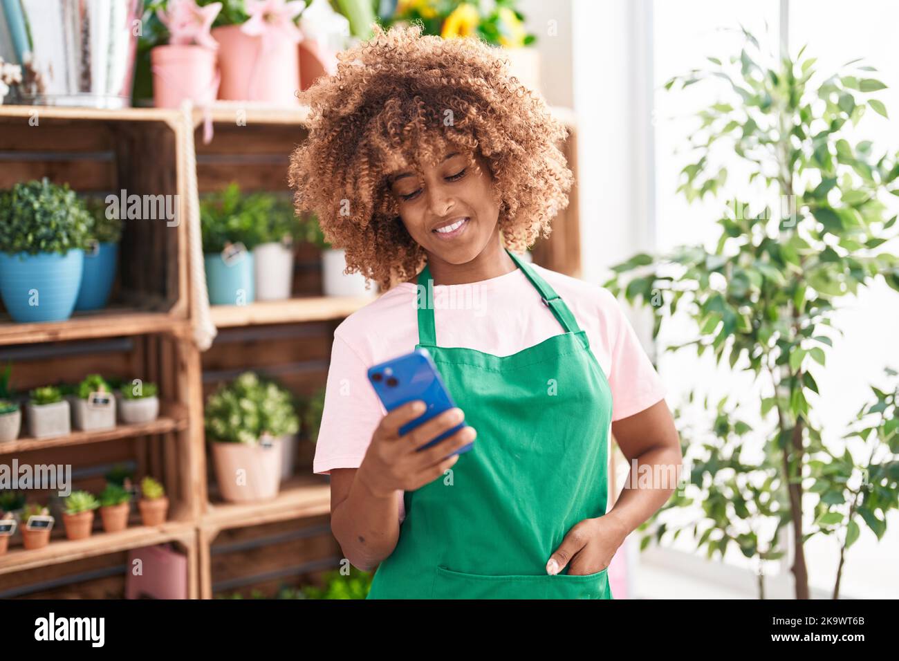 African american woman florist smiling confident using smartphone at ...