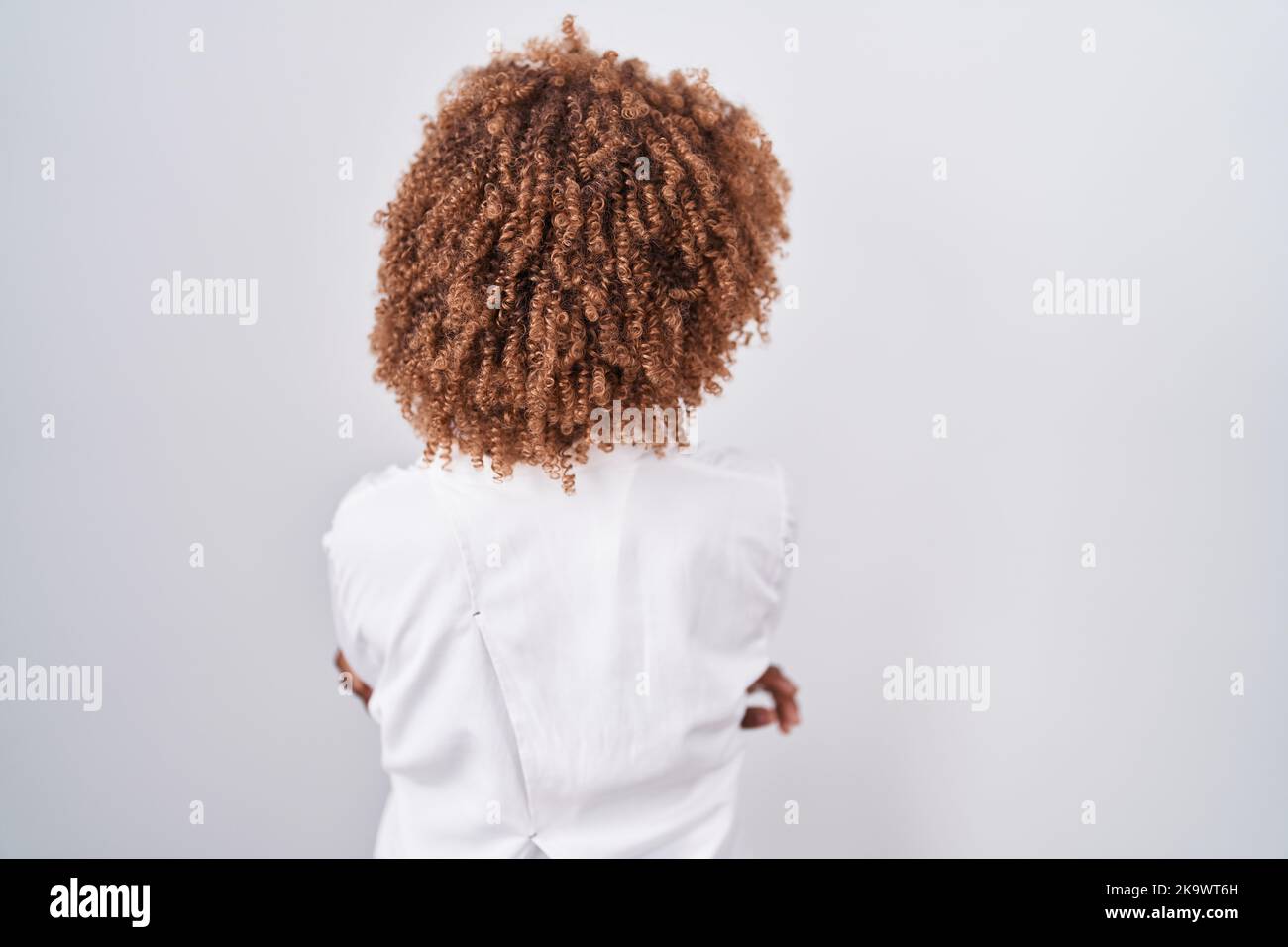 Young hispanic woman with curly hair standing over white background ...