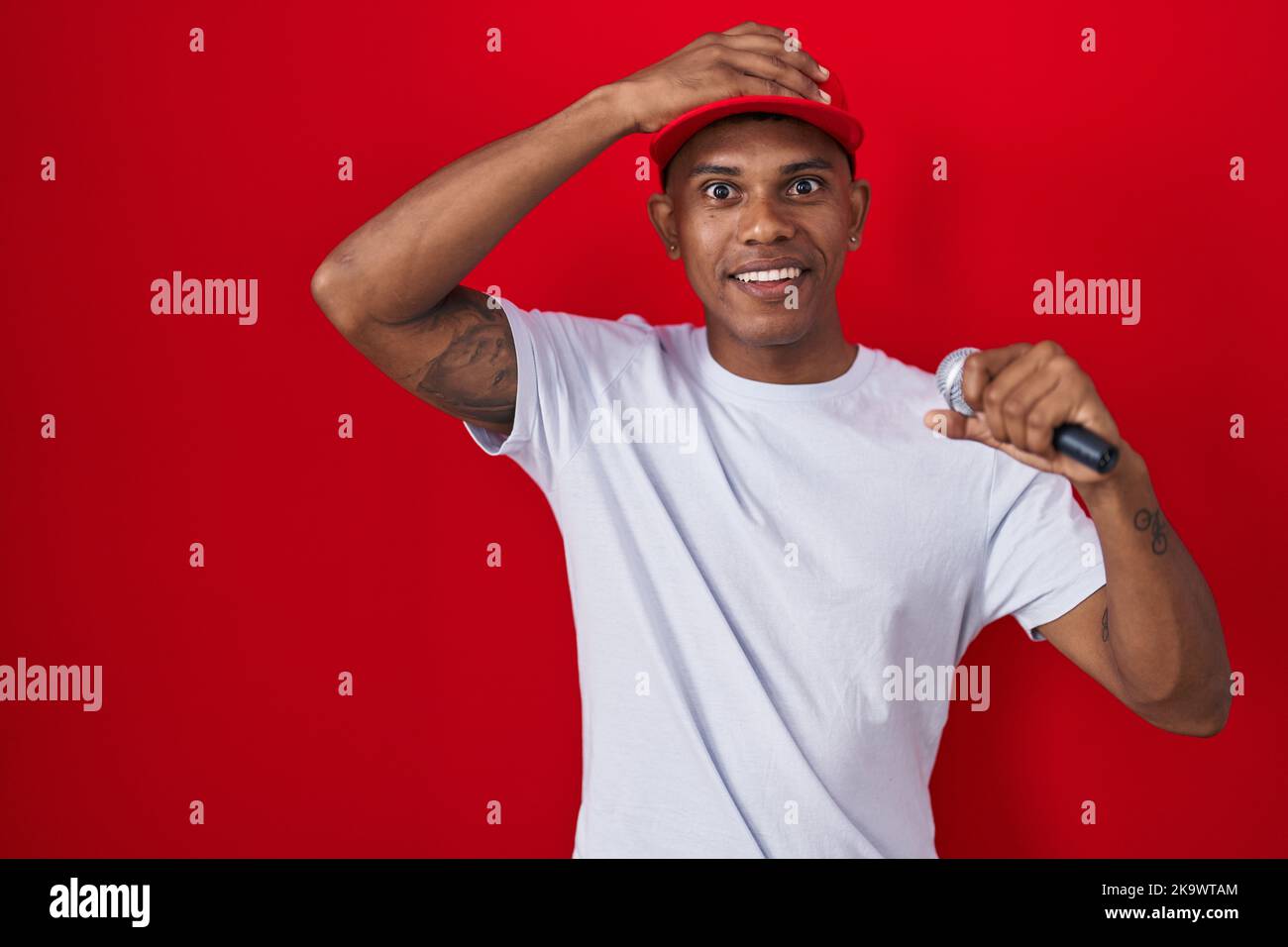 Young hispanic man singing song using microphone stressed and ...