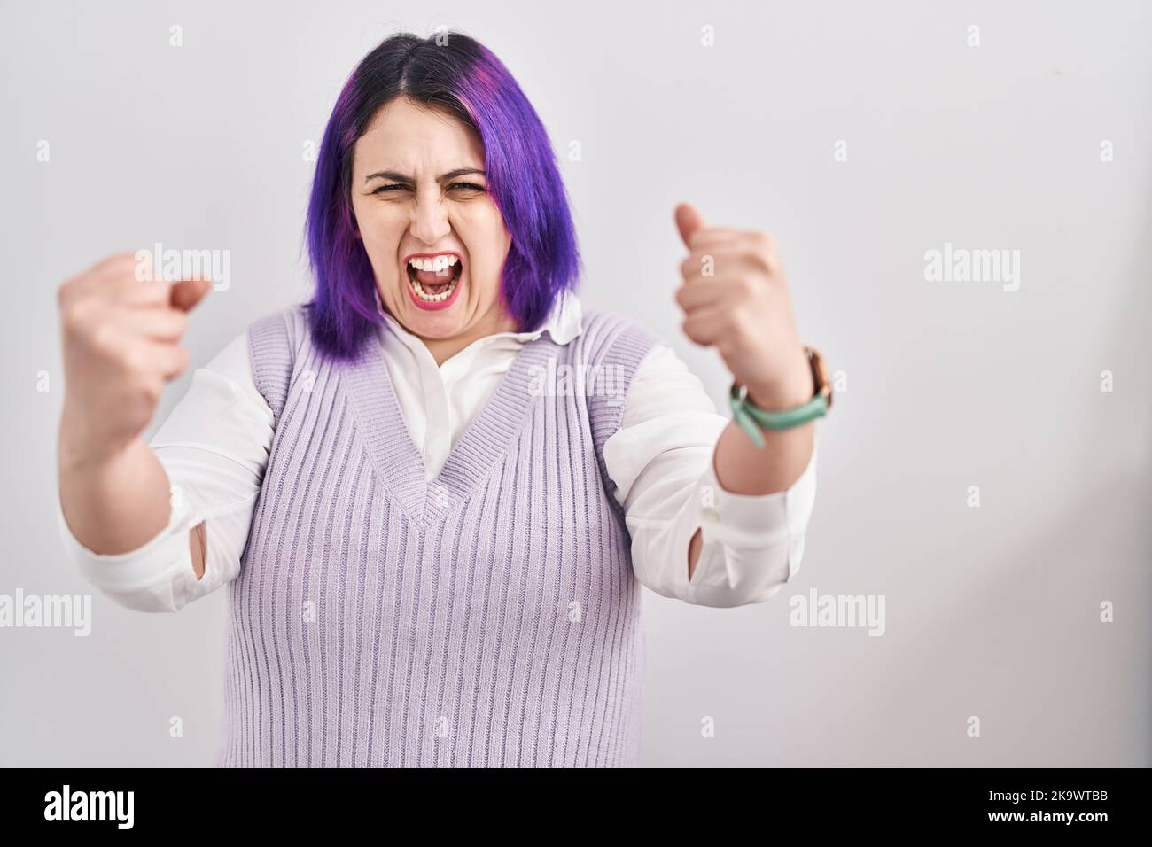Plus size woman wit purple hair standing over white background angry ...