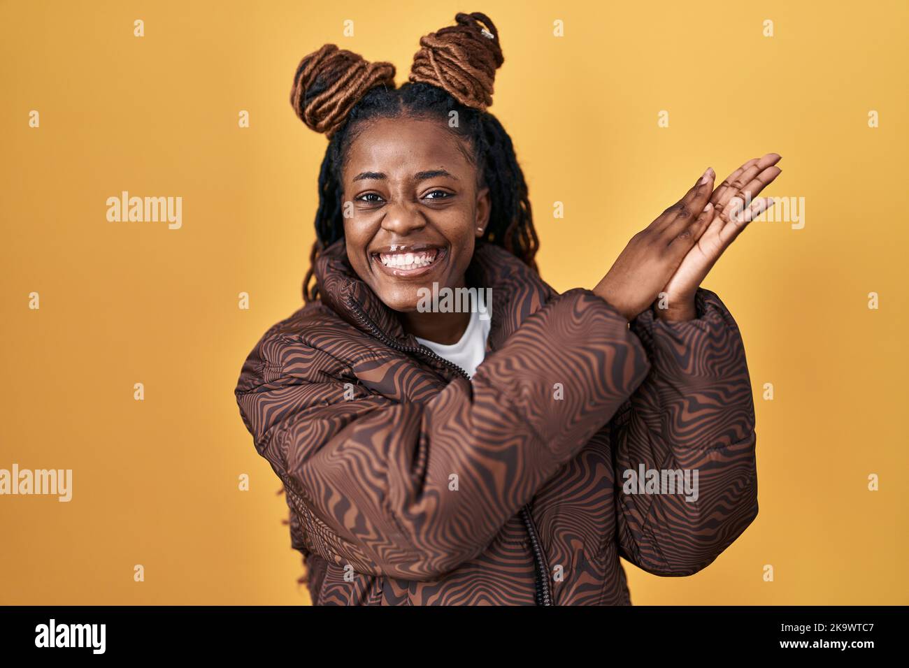 African woman with braided hair standing over yellow background ...