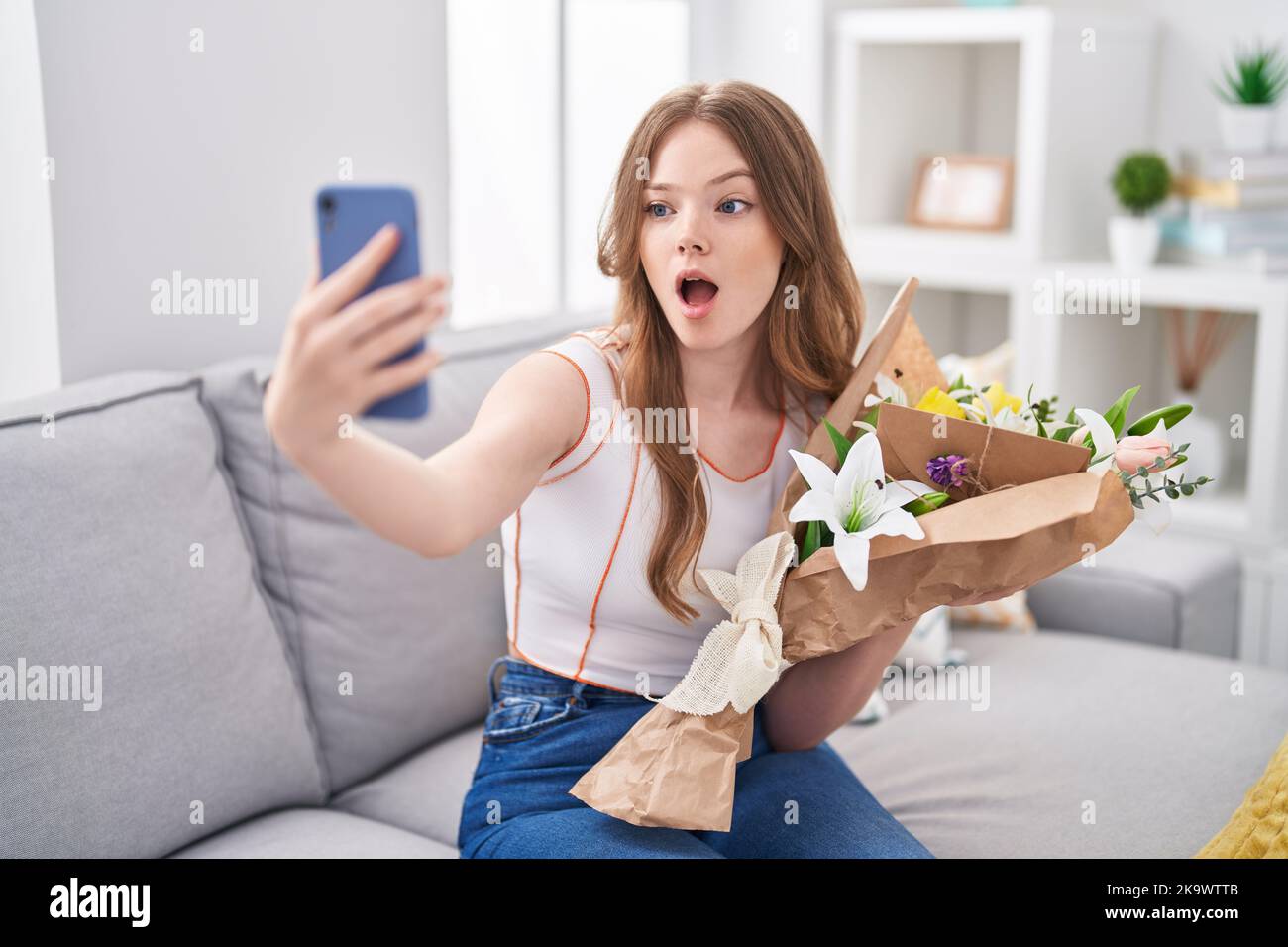 Caucasian woman holding bouquet of white flowers taking a selfie ...