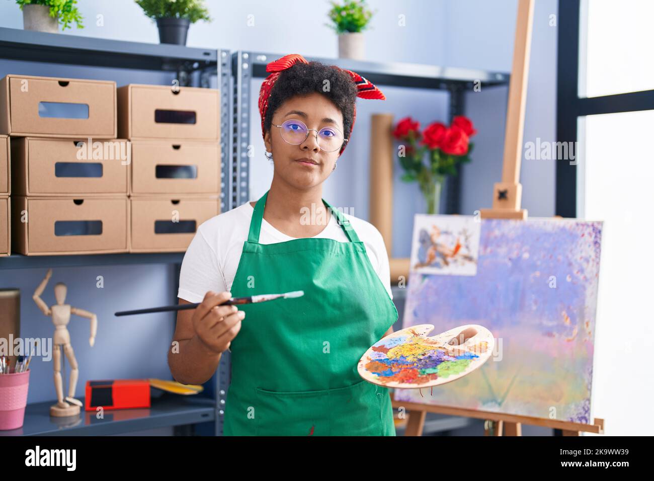 Young african american woman drawing on canvas at art studio relaxed ...