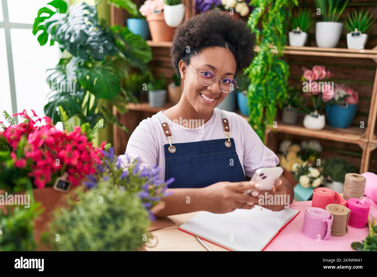 African american woman florist smiling confident using smartphone at ...