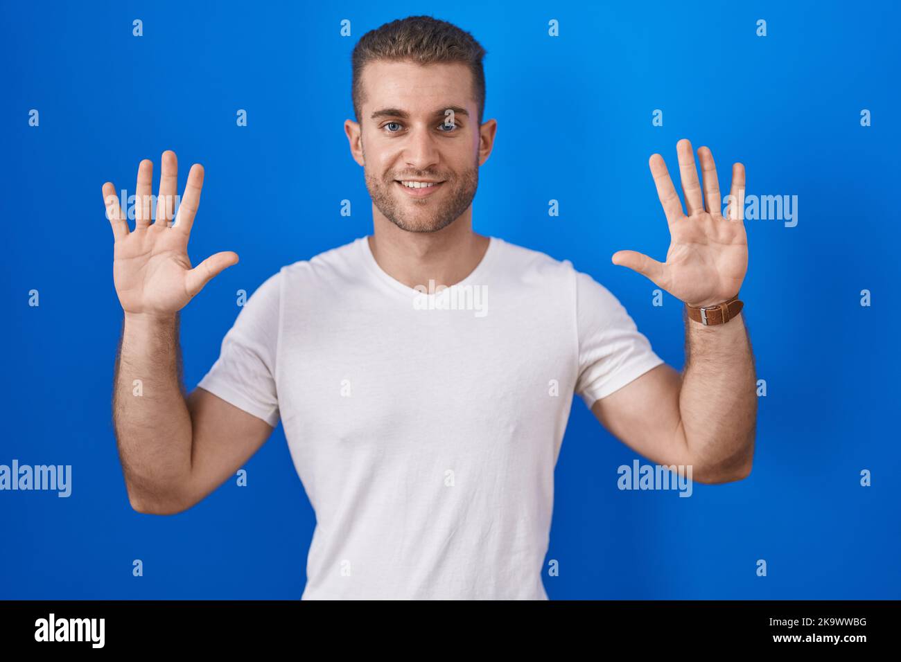 Young caucasian man standing over blue background showing and pointing ...