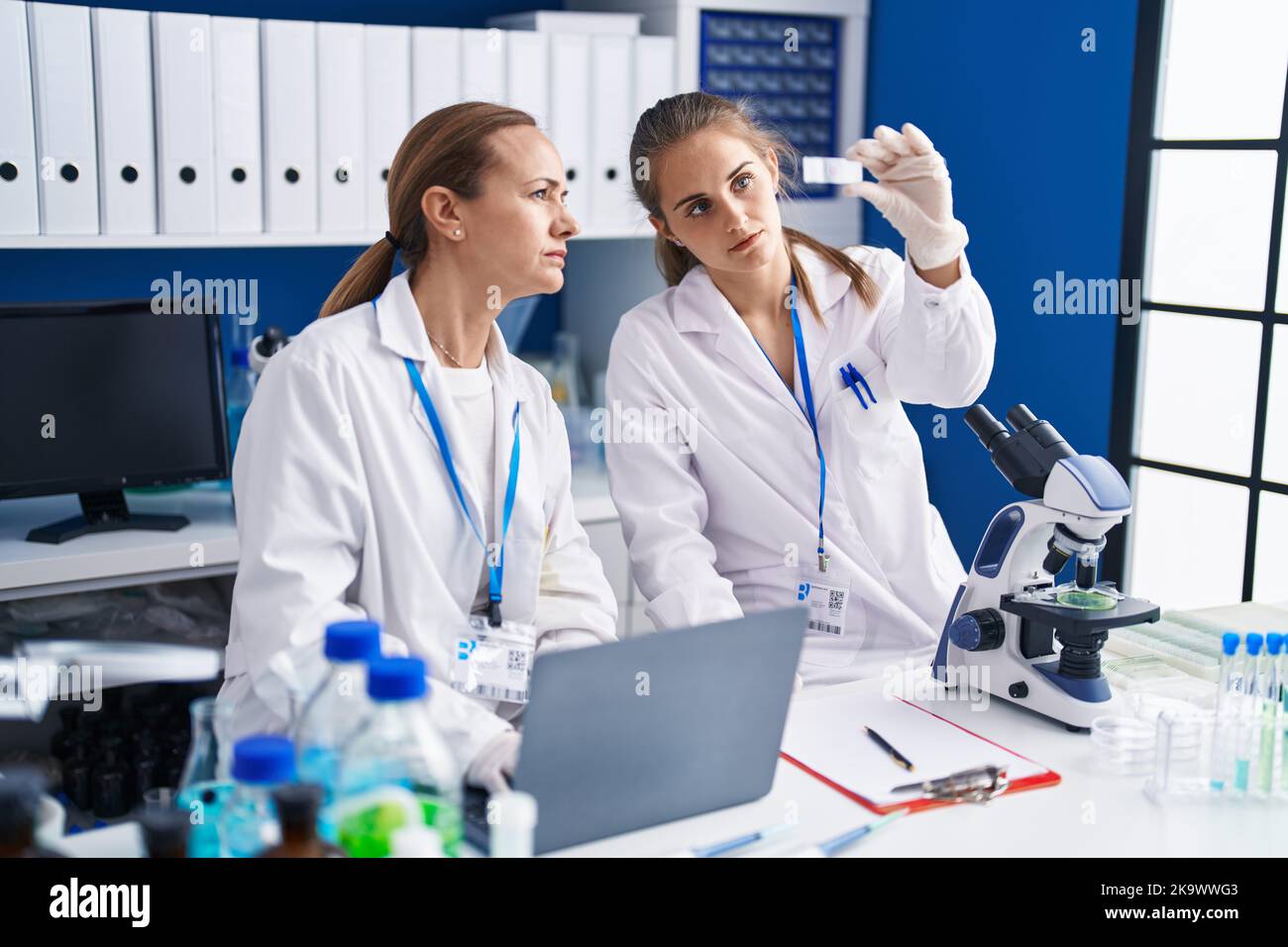 Two women scientists using laptop holding sample at laboratory Stock ...
