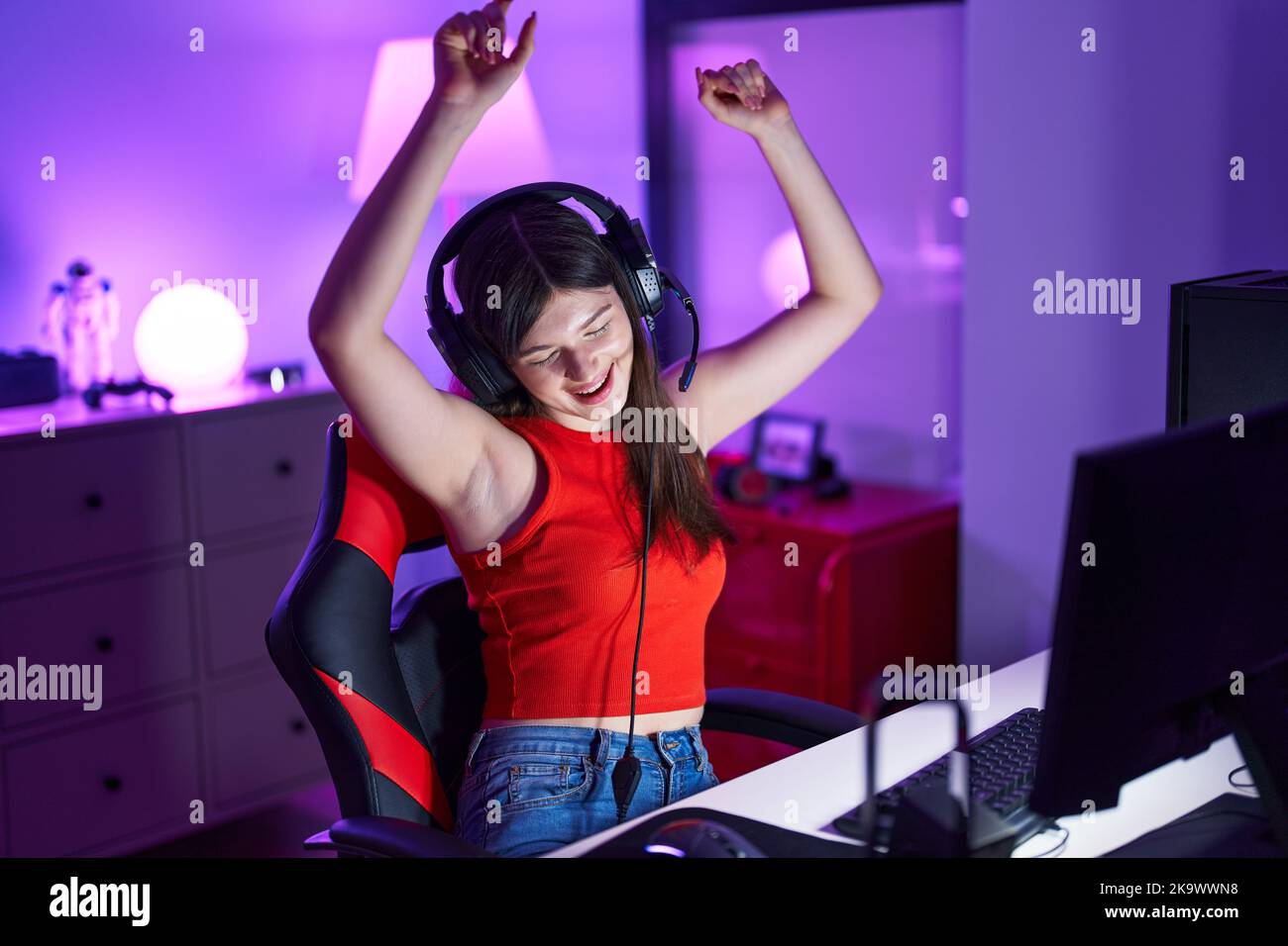 Young caucasian woman streamer playing video game listening music at ...