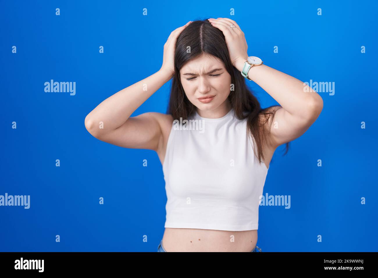 Young caucasian woman standing over blue background suffering from ...