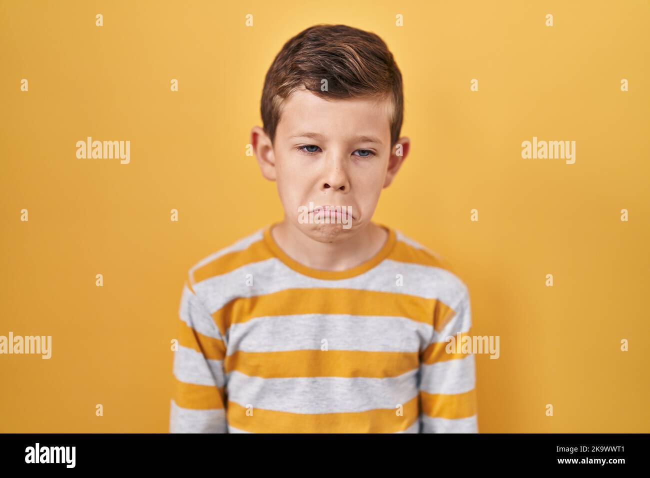 Young caucasian kid standing over yellow background depressed and worry ...