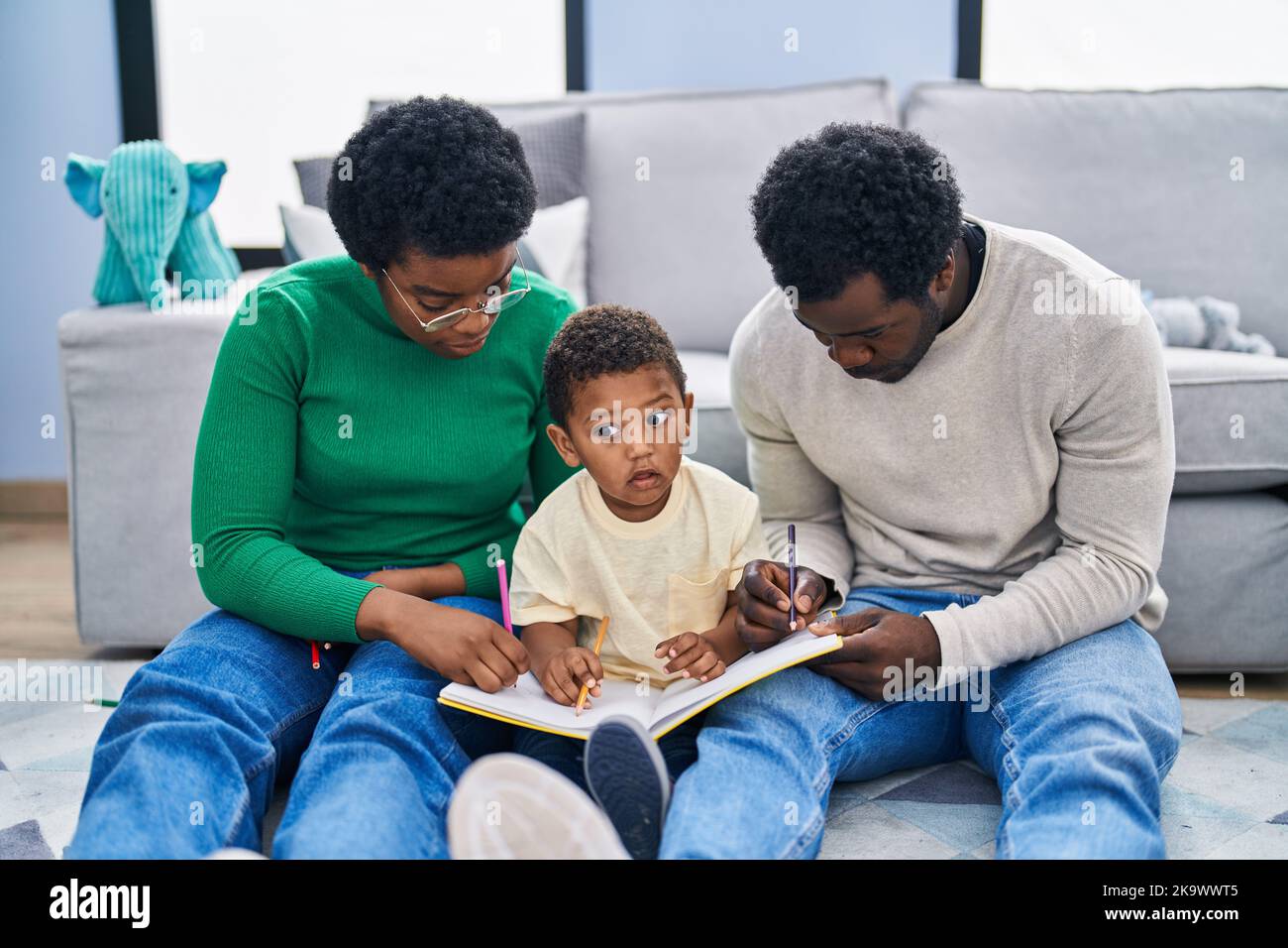 African american family drawing on notebook sitting on floor at home ...