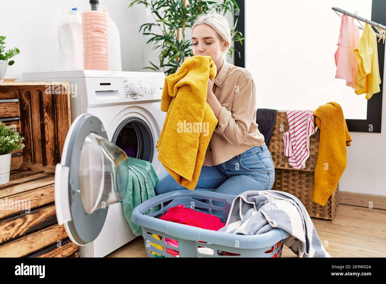 Young caucasian woman smiling confident smelling clothes at laundry ...