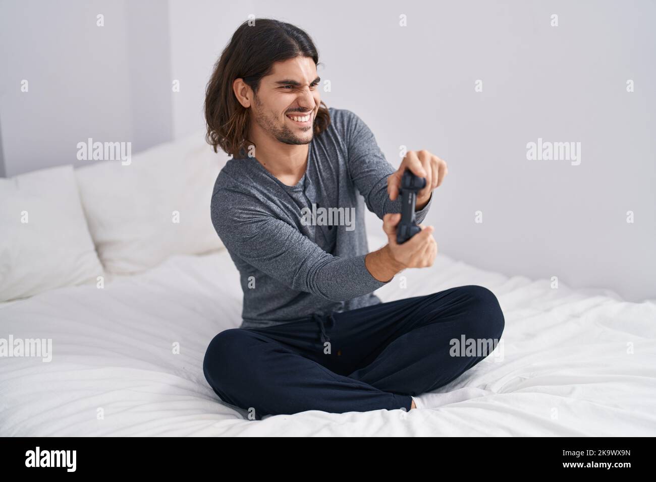 Young hispanic man playing video game sitting on bed at bedroom Stock ...