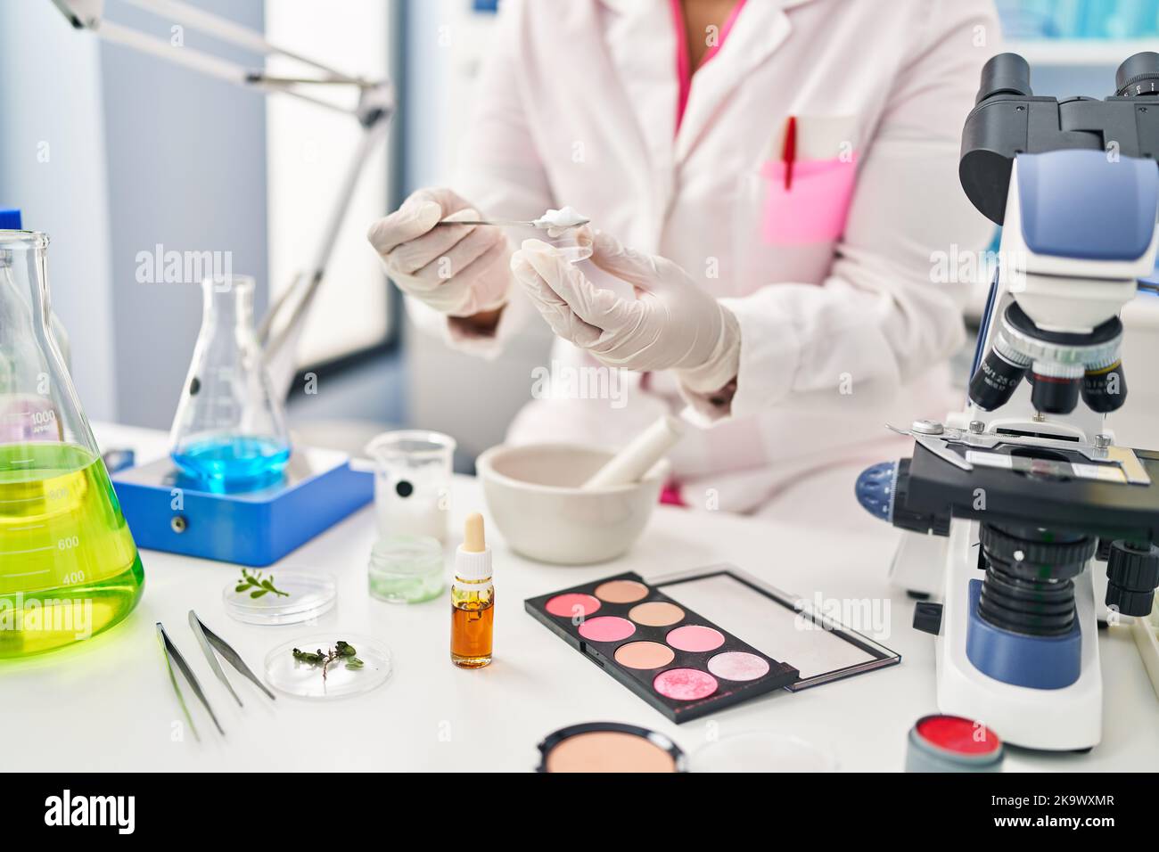 Young hispanic woman wearing scientist uniform mixing powder at ...