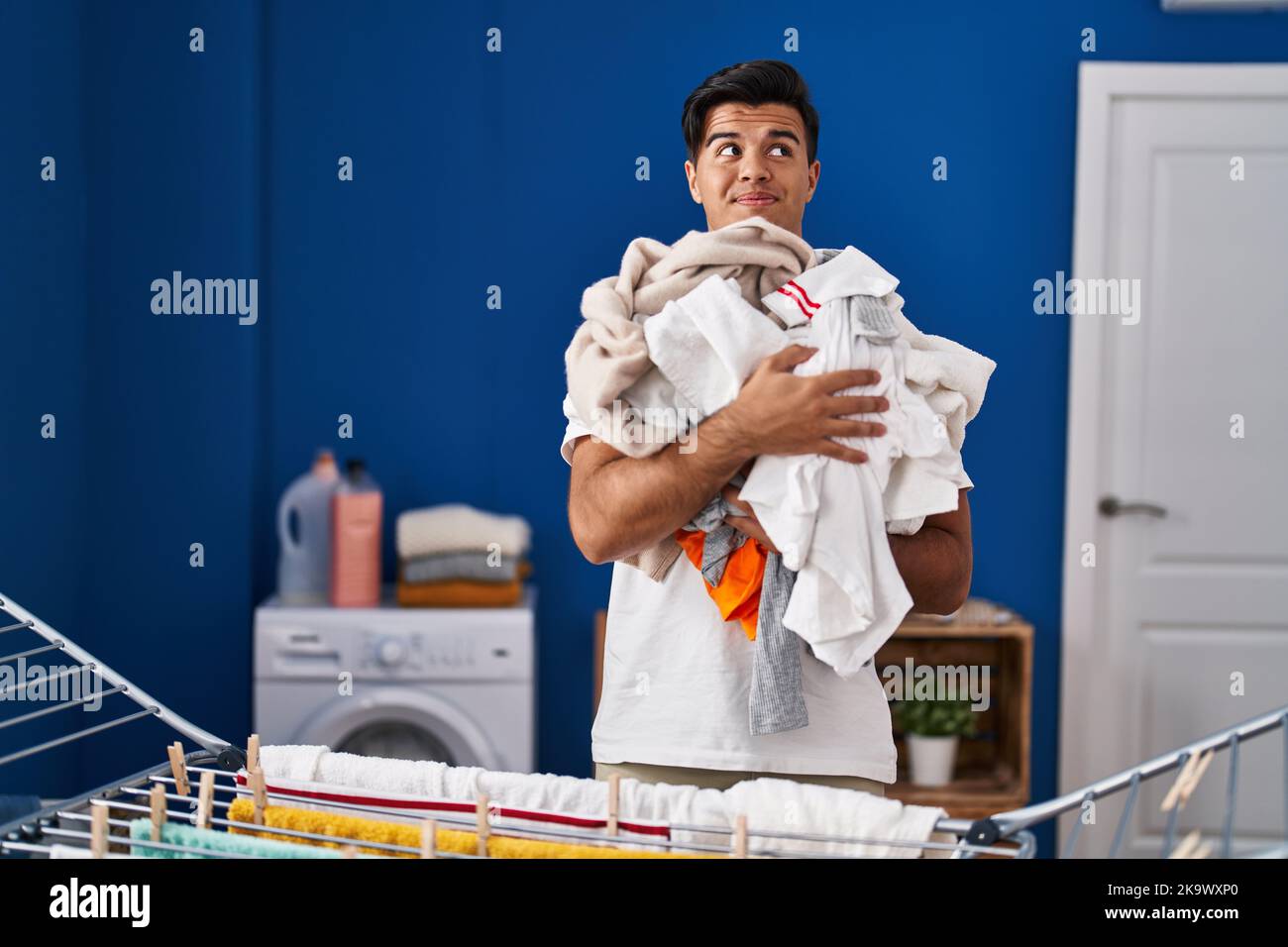 Hispanic man hanging clothes at clothesline smiling looking to the side ...