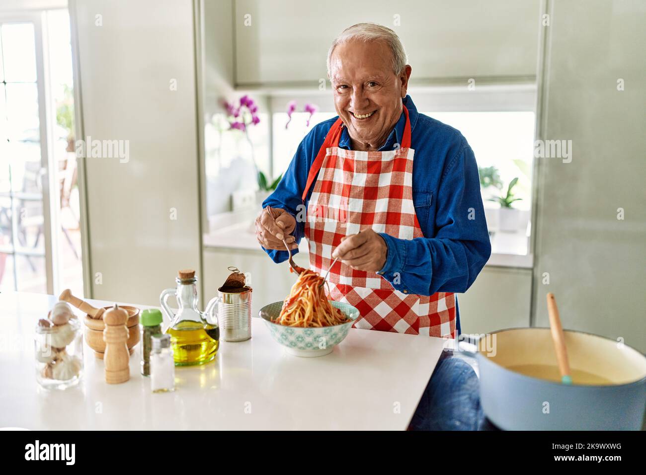 Senior man smiling confident mixing tomato sauce with spaghetti at ...