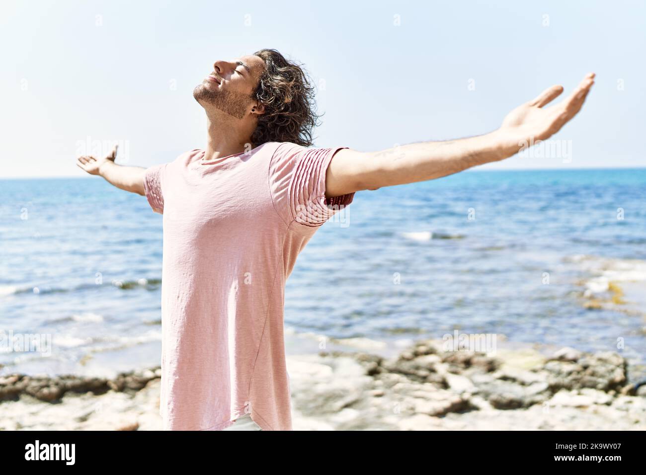 Young hispanic man breathing standing with arms open at the beach Stock ...