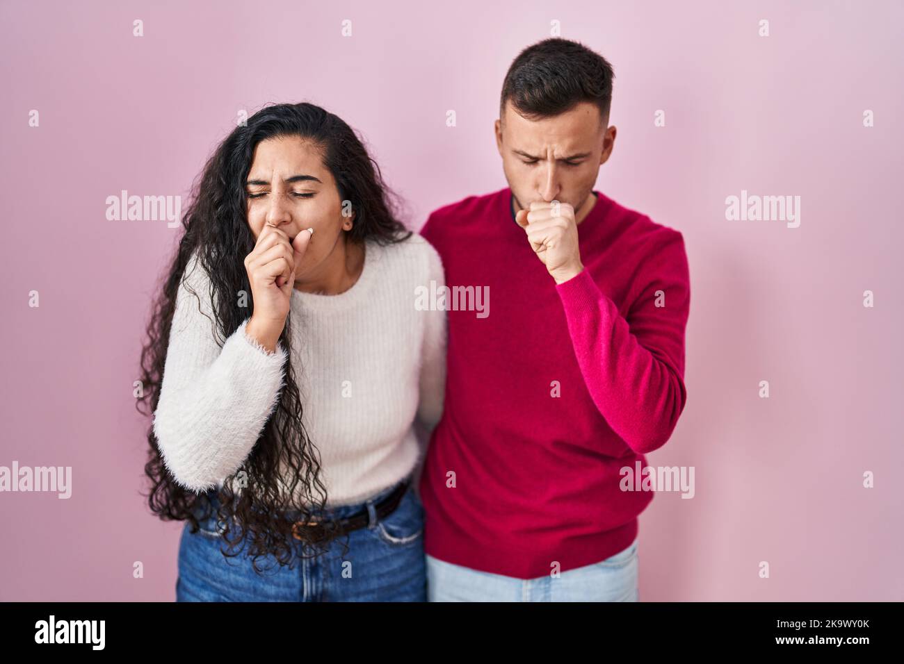 Young hispanic couple standing over pink background feeling unwell and ...