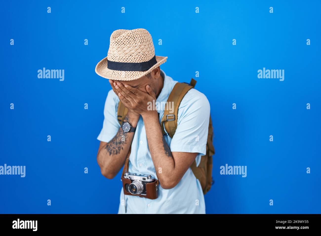 Brazilian young man holding vintage camera with sad expression covering ...