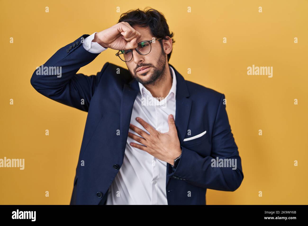 Handsome latin man standing over yellow background touching forehead ...