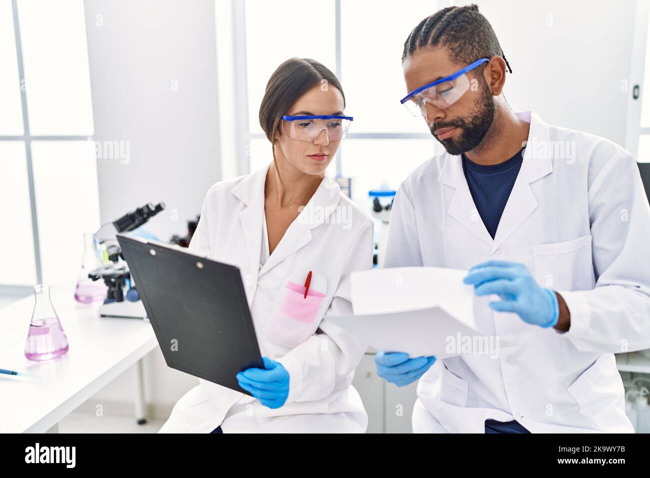 Man and woman scientist partners reading documents at laboratory Stock ...
