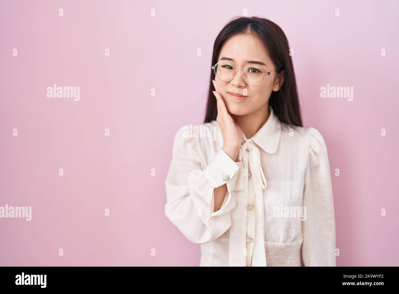 Young chinese woman standing over pink background touching mouth with ...