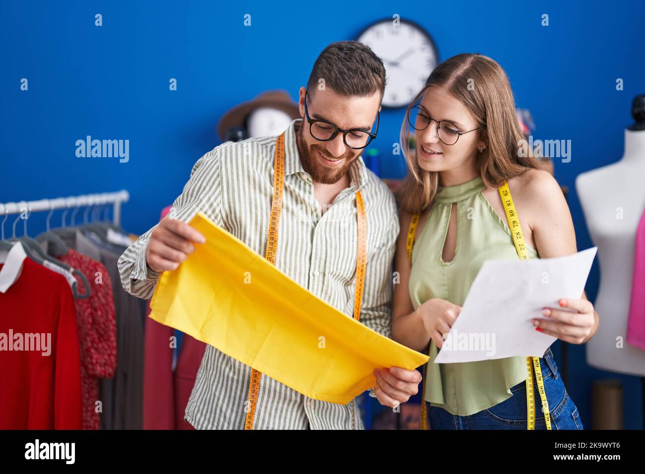 Man and woman tailors holding cloth looking clothing design at clothing ...