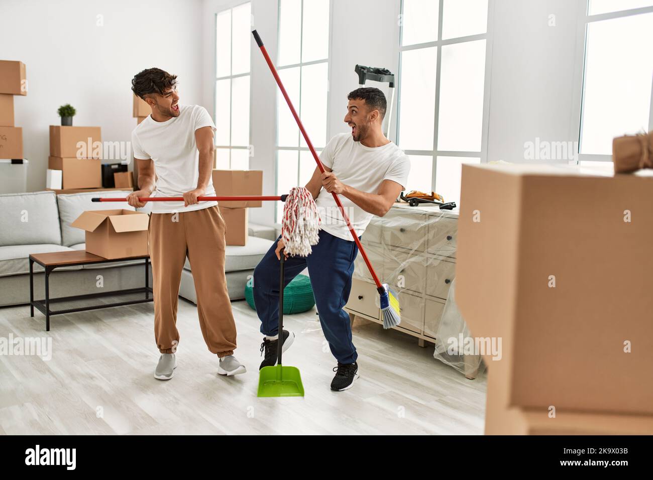 Two hispanic men couple cleaning and dancing at new home Stock Photo ...