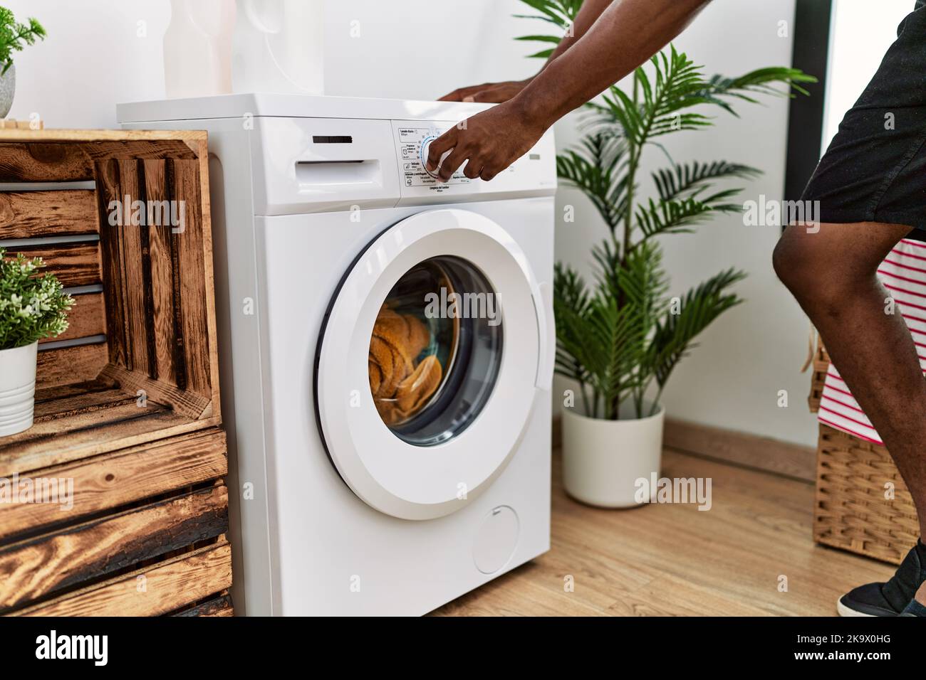 Young african american man cleaning clothes using washing machine at ...