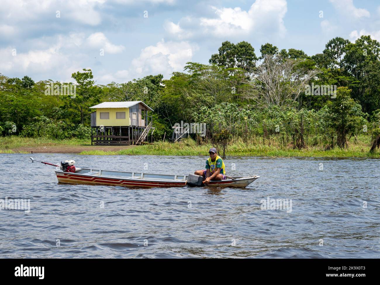 A young Brazilian man fishing in a boat on the Amazon river ...
