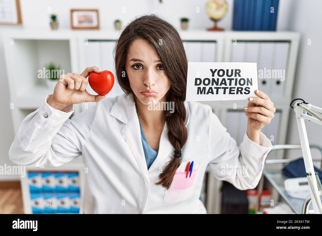 Young doctor woman holding your donation matters banner at the clinic ...