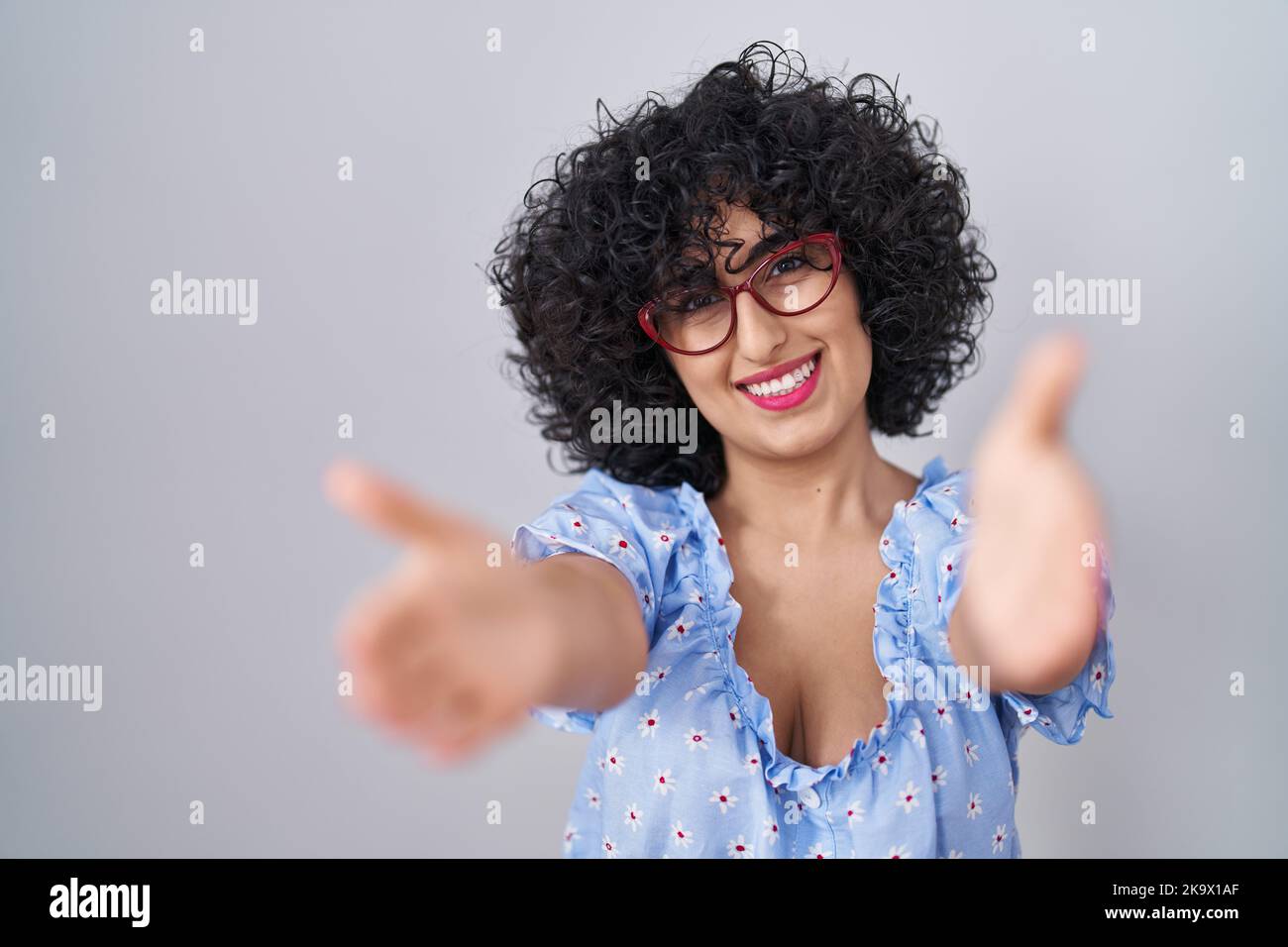 Young brunette woman with curly hair wearing glasses over isolated ...