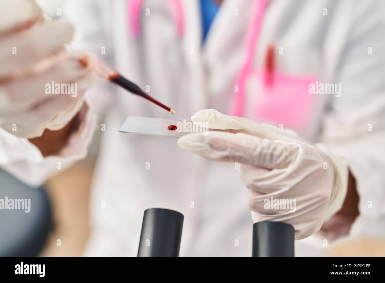 Young chinese woman wearing scientist uniform analysing blood at ...