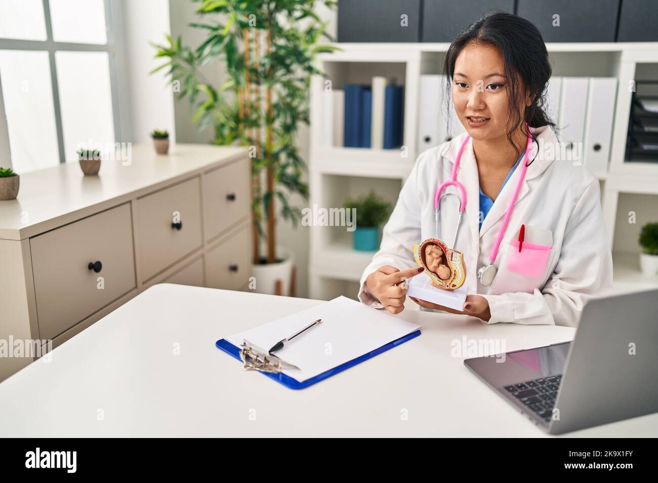 Young chinese woman wearing doctor uniform holding anatomical model of ...