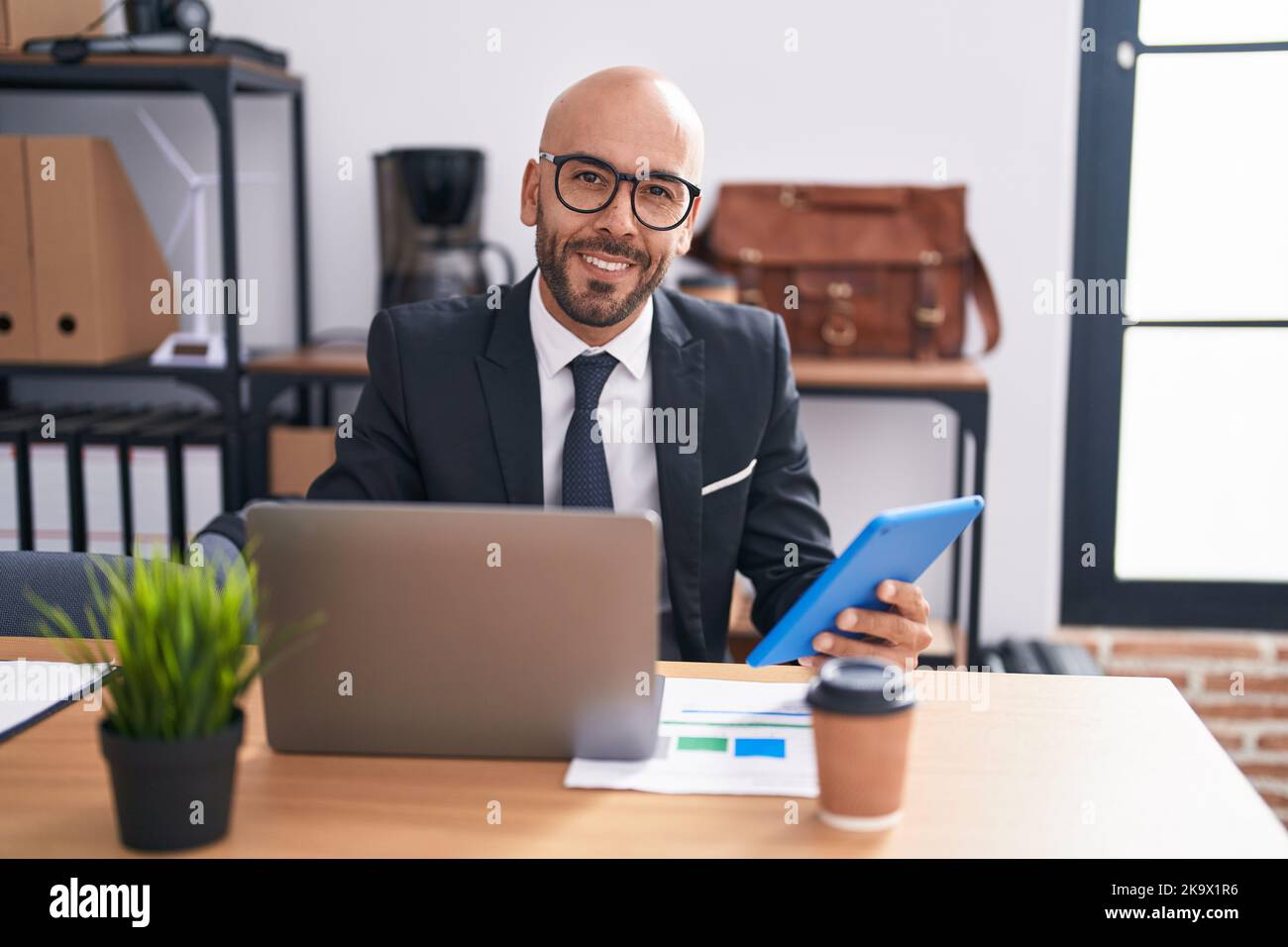 Young bald man business worker using touchpad and laptop at office ...