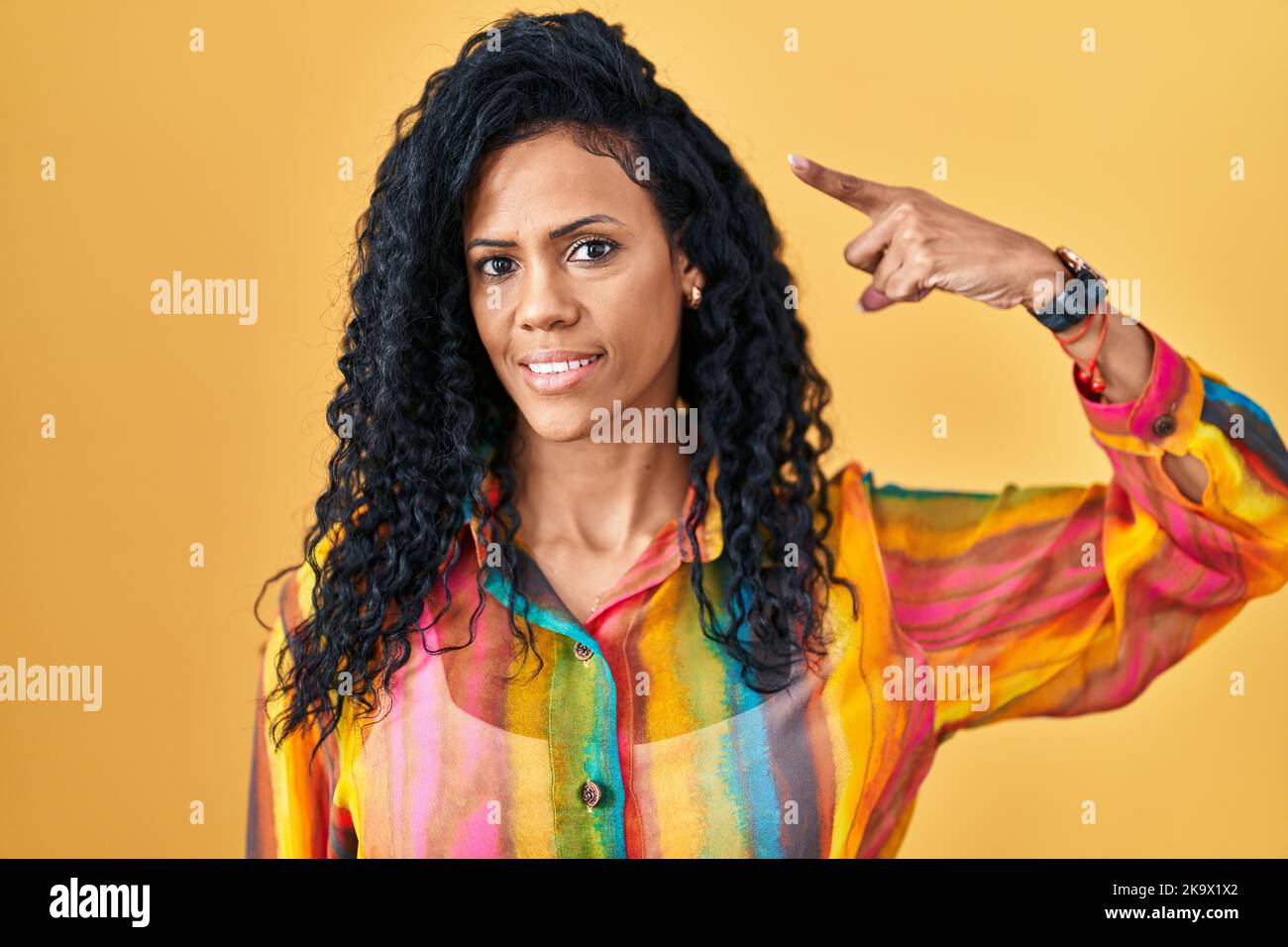Middle age hispanic woman standing over yellow background smiling ...