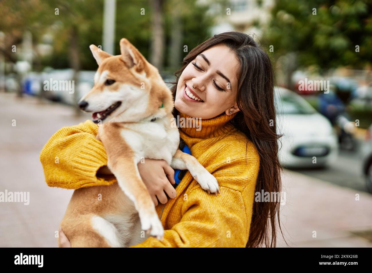 Beautiful young woman hugging happy shiba inu dog at street Stock Photo ...