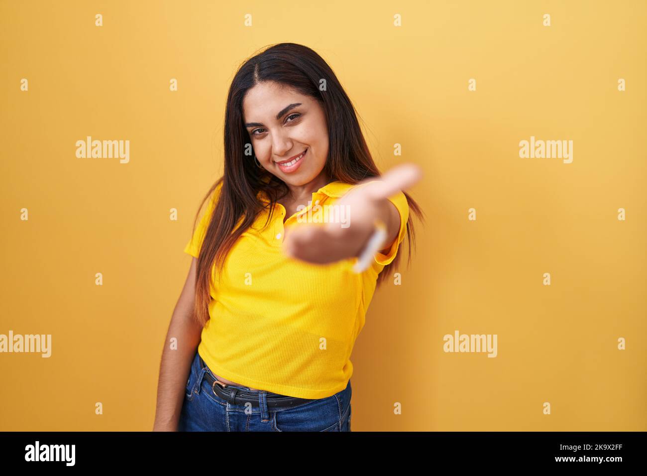 Young arab woman standing over yellow background smiling cheerful ...