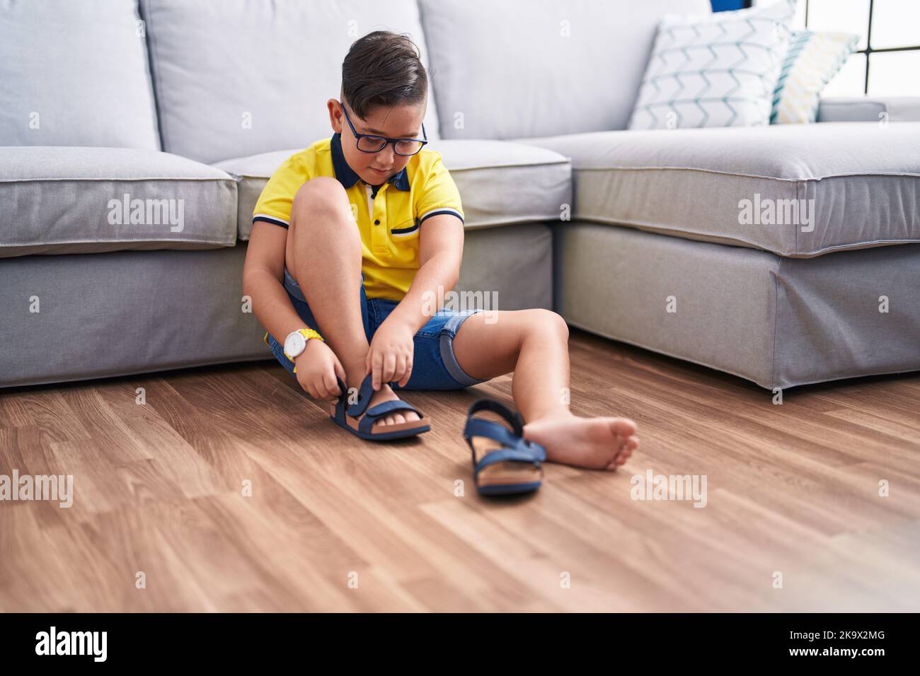 Adorable hispanic boy sitting on floor wearing slippers at home Stock ...