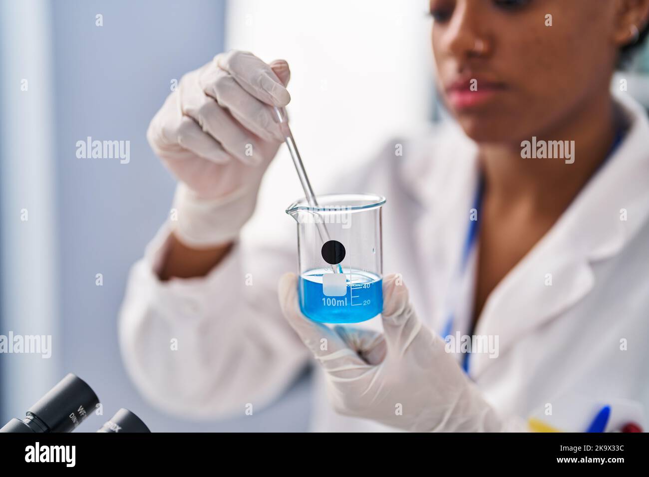 African american woman scientist mixing liquid on glass at laboratory ...