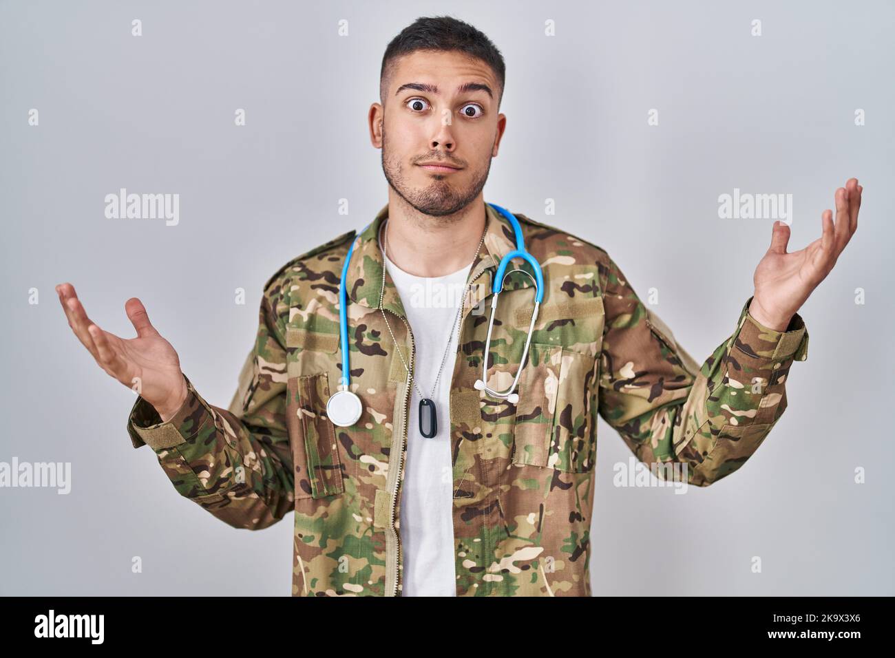 Young hispanic doctor wearing camouflage army uniform shouting and ...