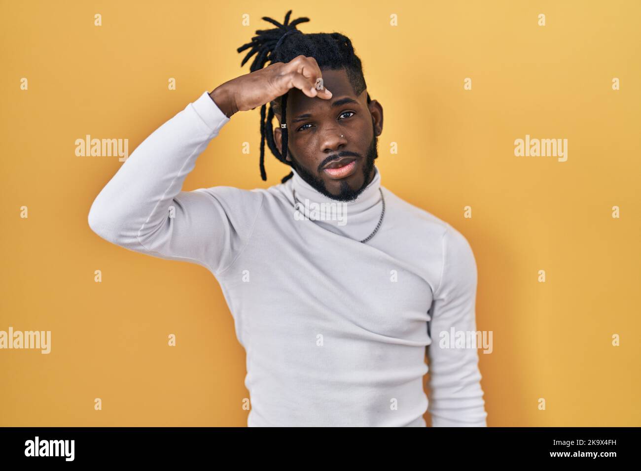 African man with dreadlocks wearing turtleneck sweater over yellow ...