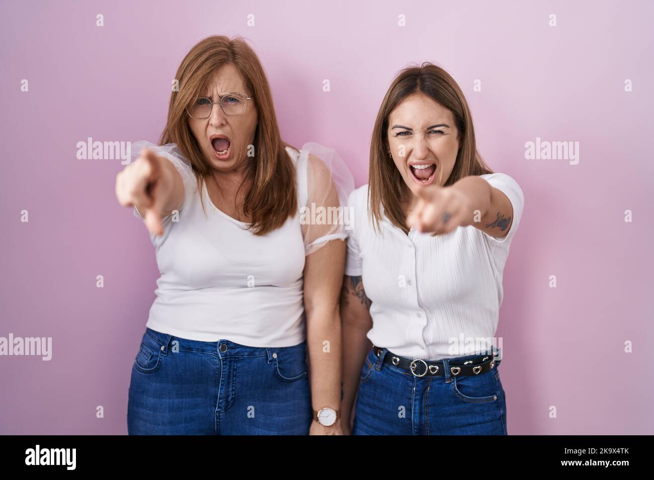 Hispanic mother and daughter wearing casual white t shirt over pink ...