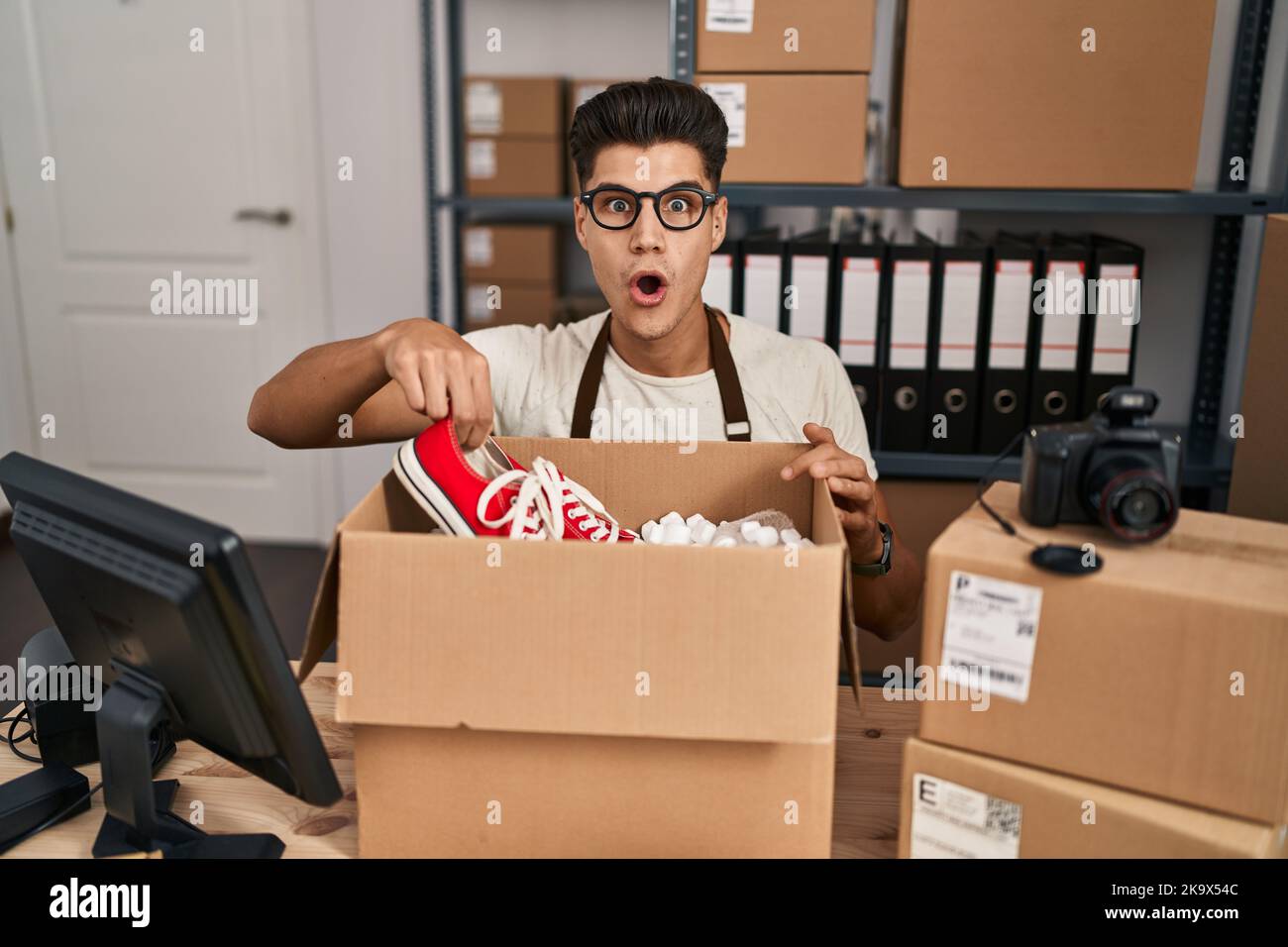 Young hispanic man working at small business ecommerce scared and ...